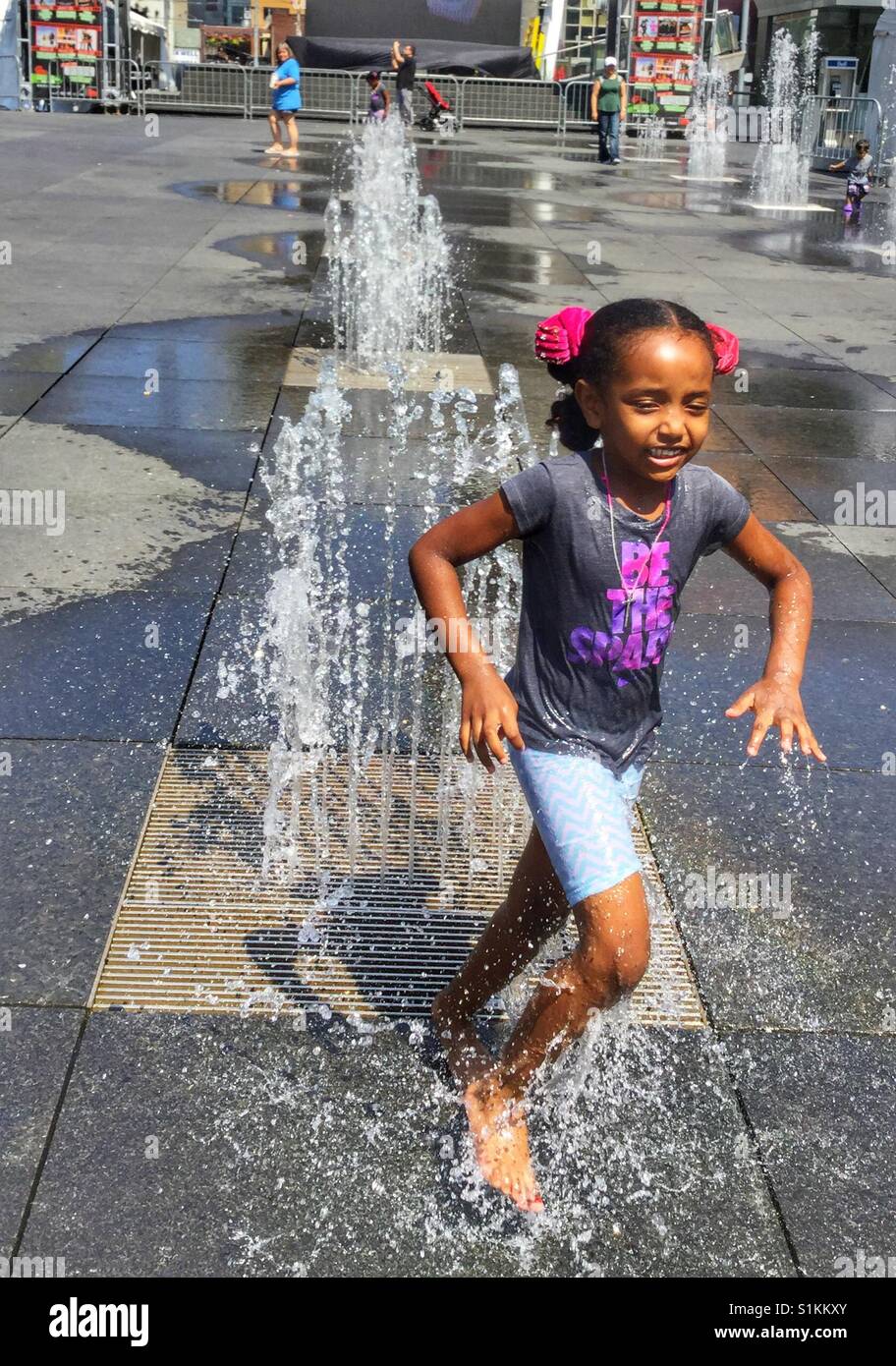 Young girl running through city fountains to stay cool Stock Photo - Alamy