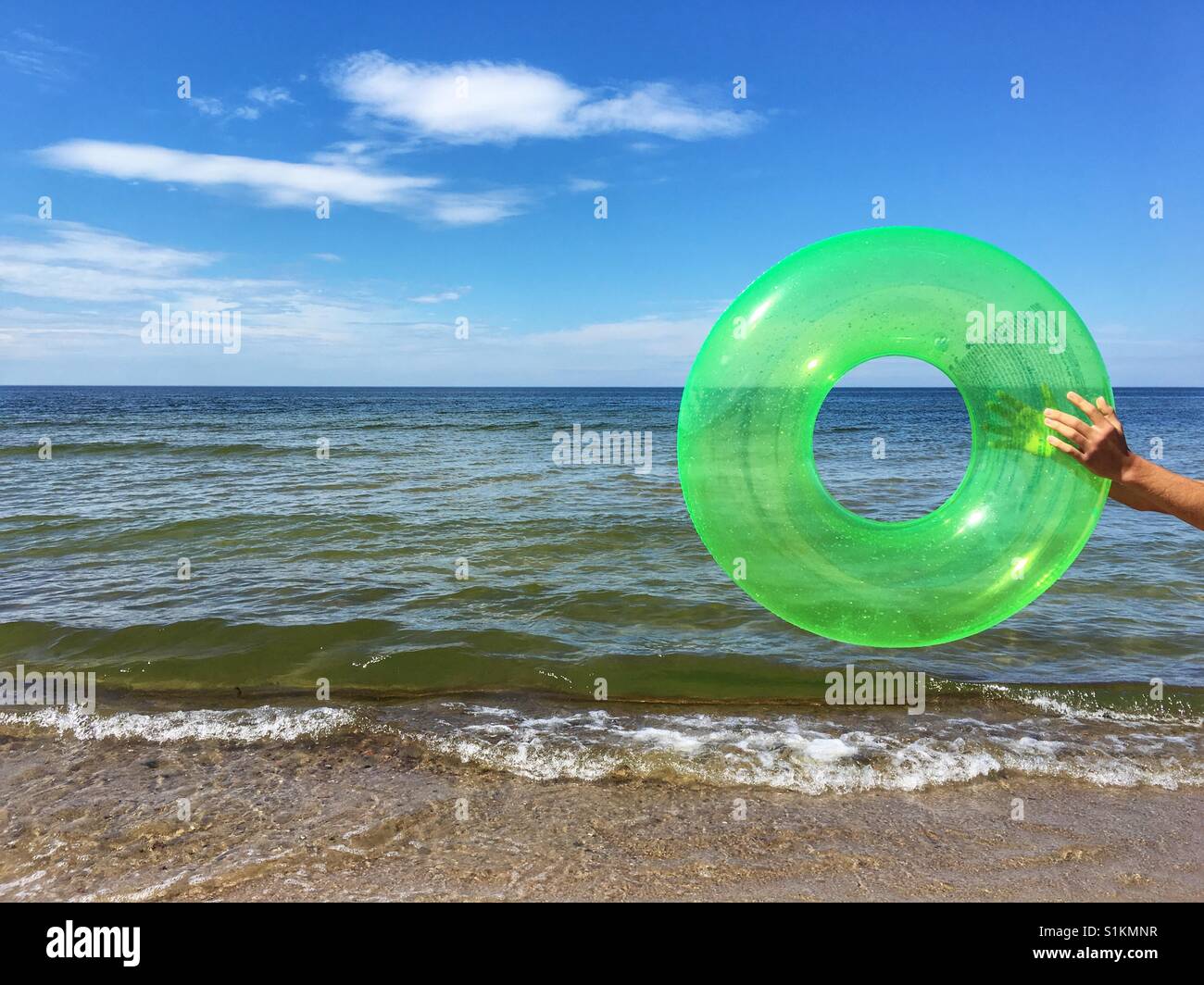 Hands of a child holding an inflatable green circle on a beach Stock ...