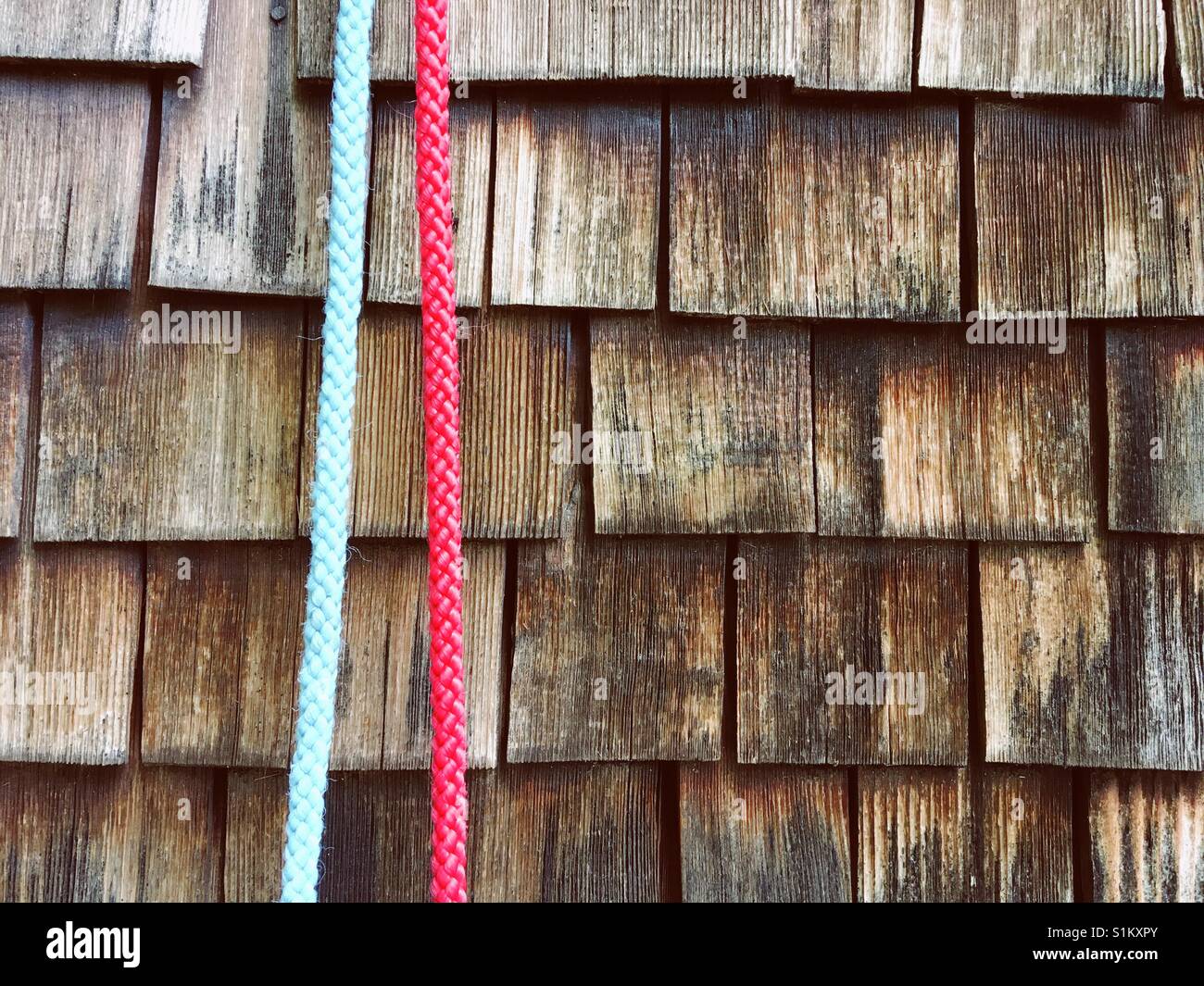 Part of a shingled wall with a red and a blue rope hanging down Stock ...