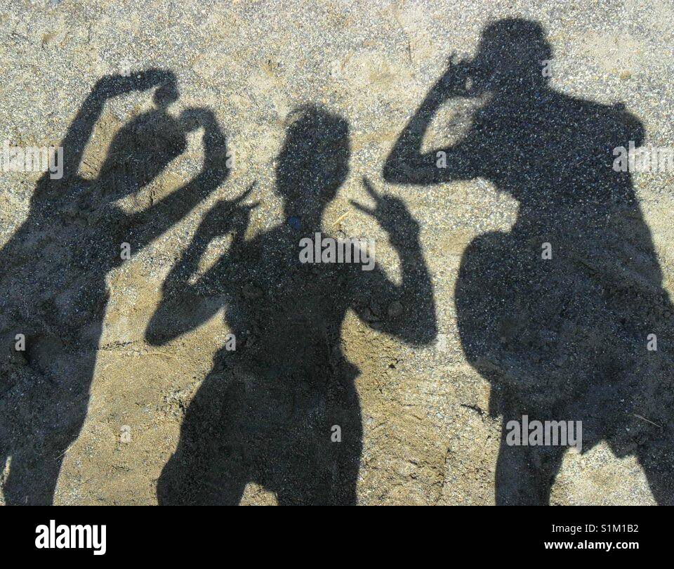 Friends posed creating a comical-look shadows by the beach Stock Photo ...