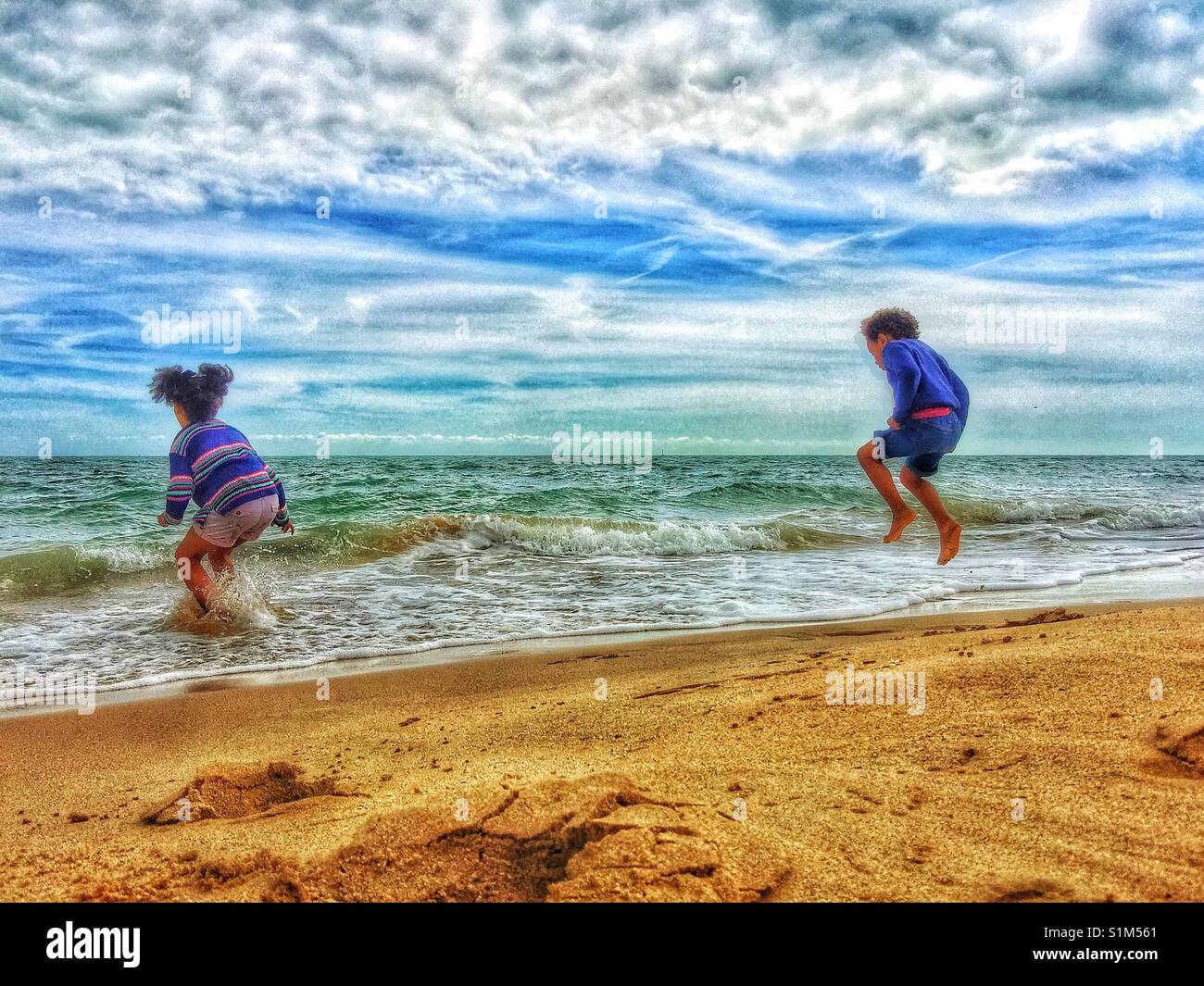 Children at the beach jumping in the surf Stock Photo - Alamy