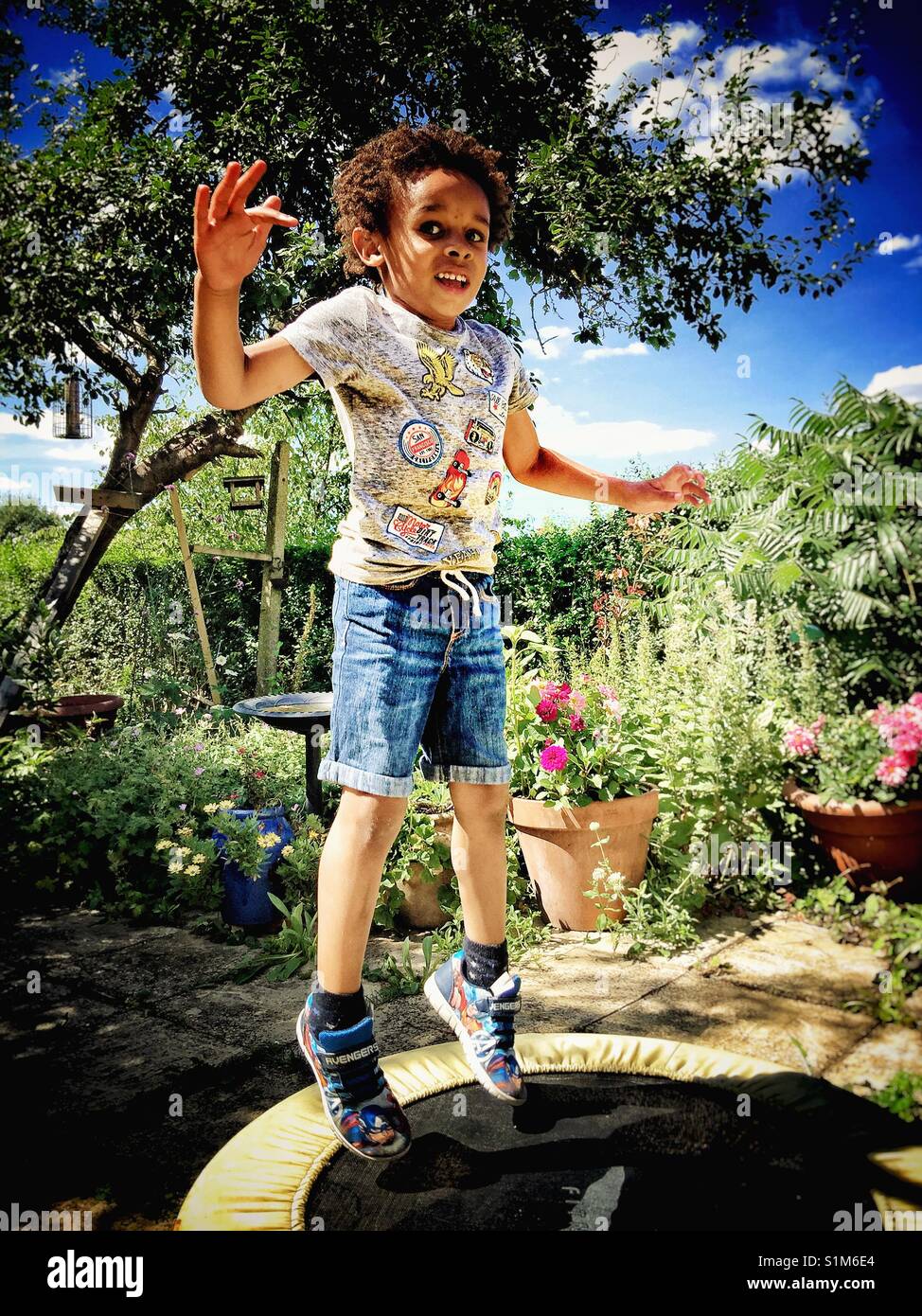 A little boy in a garden jumping on a trampoline Stock Photo - Alamy