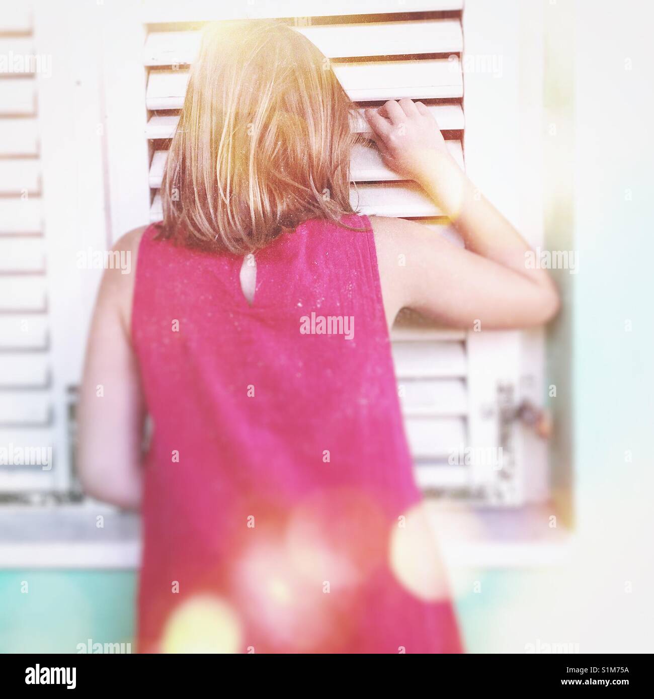 Curious little girl looking through window blinds Stock Photo - Alamy