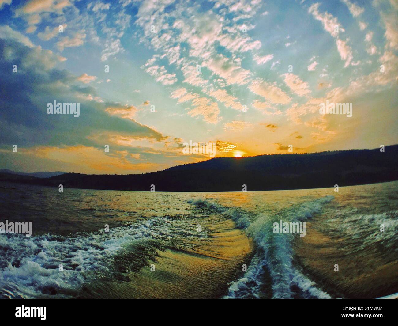 Looking back at sunset over a mountain from a boat Stock Photo - Alamy