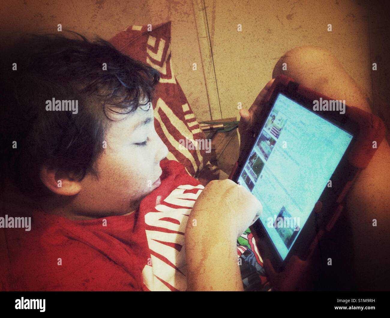 A young boy playing on an iPad Stock Photo - Alamy