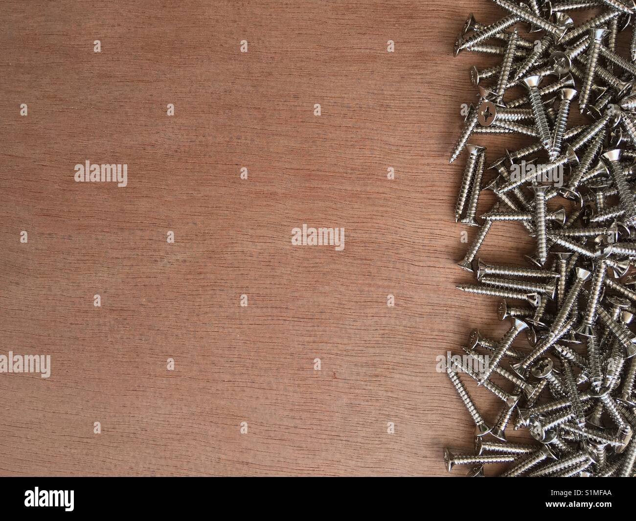 Metal screws on wood table. Top view Stock Photo - Alamy