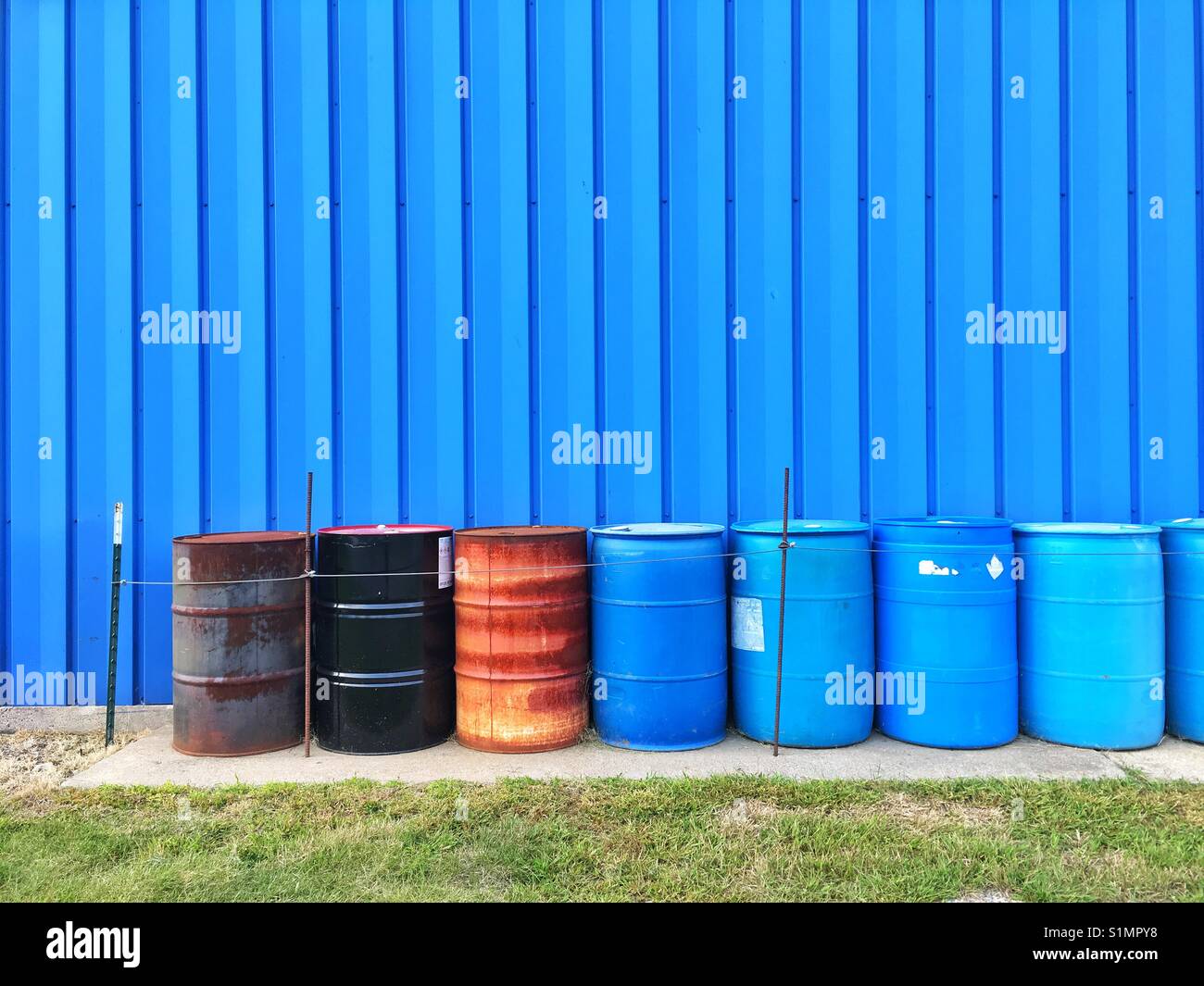 Blue metal wall and row of barrels in front Stock Photo - Alamy