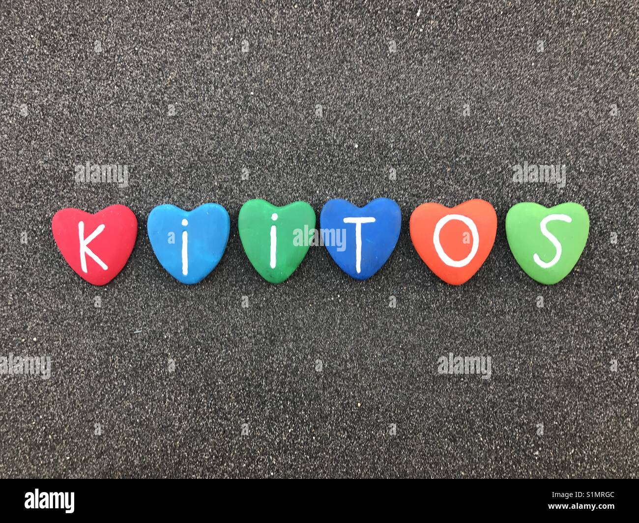 Kiitos, finnish thank you with colored heart stones over black volcanic ...