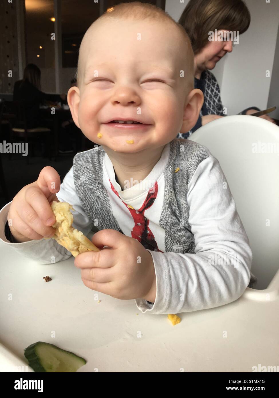 Happy baby boy on breakfast table eating waffle Stock Photo - Alamy