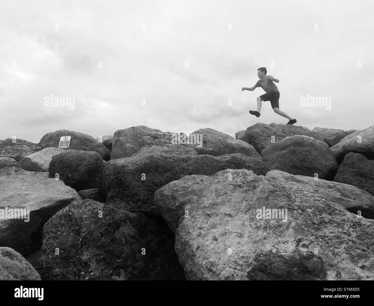 Boy leaping over boulders Stock Photo - Alamy