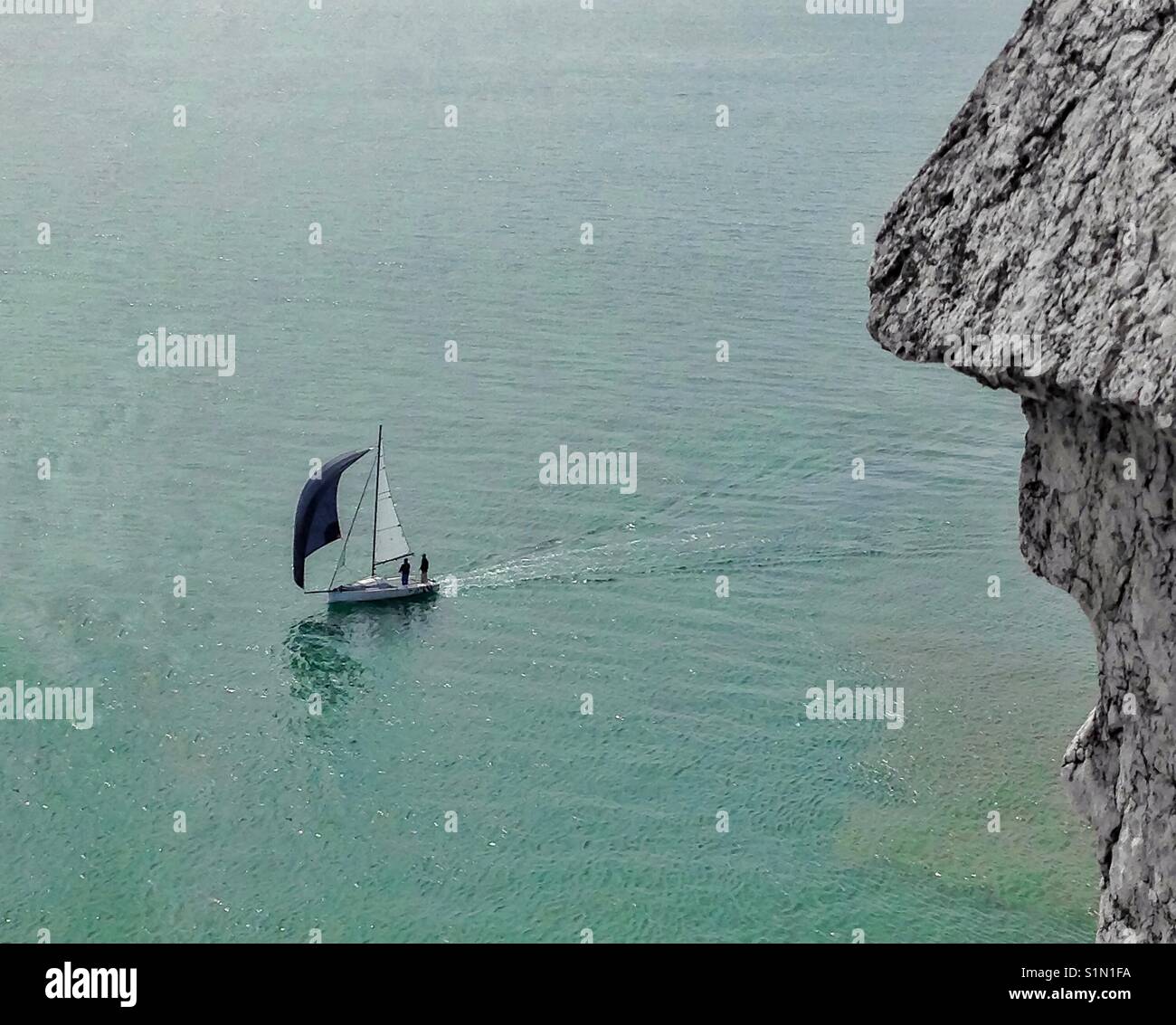 Boat sailing on a beautiful green ocean with a rock from a construction ...