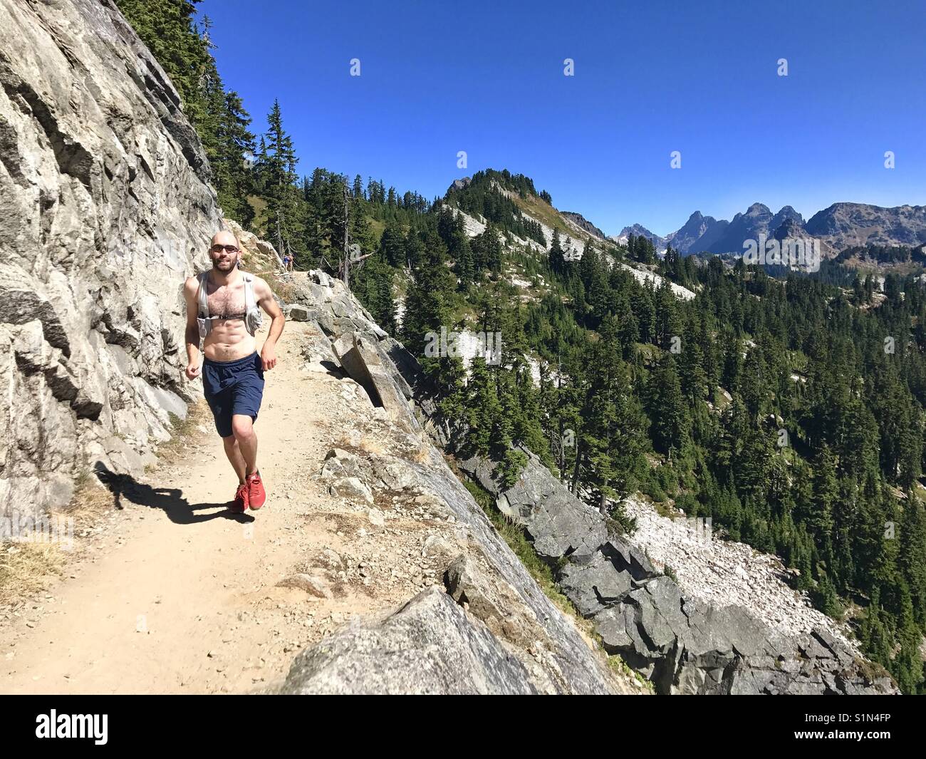 Fit trail runner in the mountains of the North Cascades, running in a ...