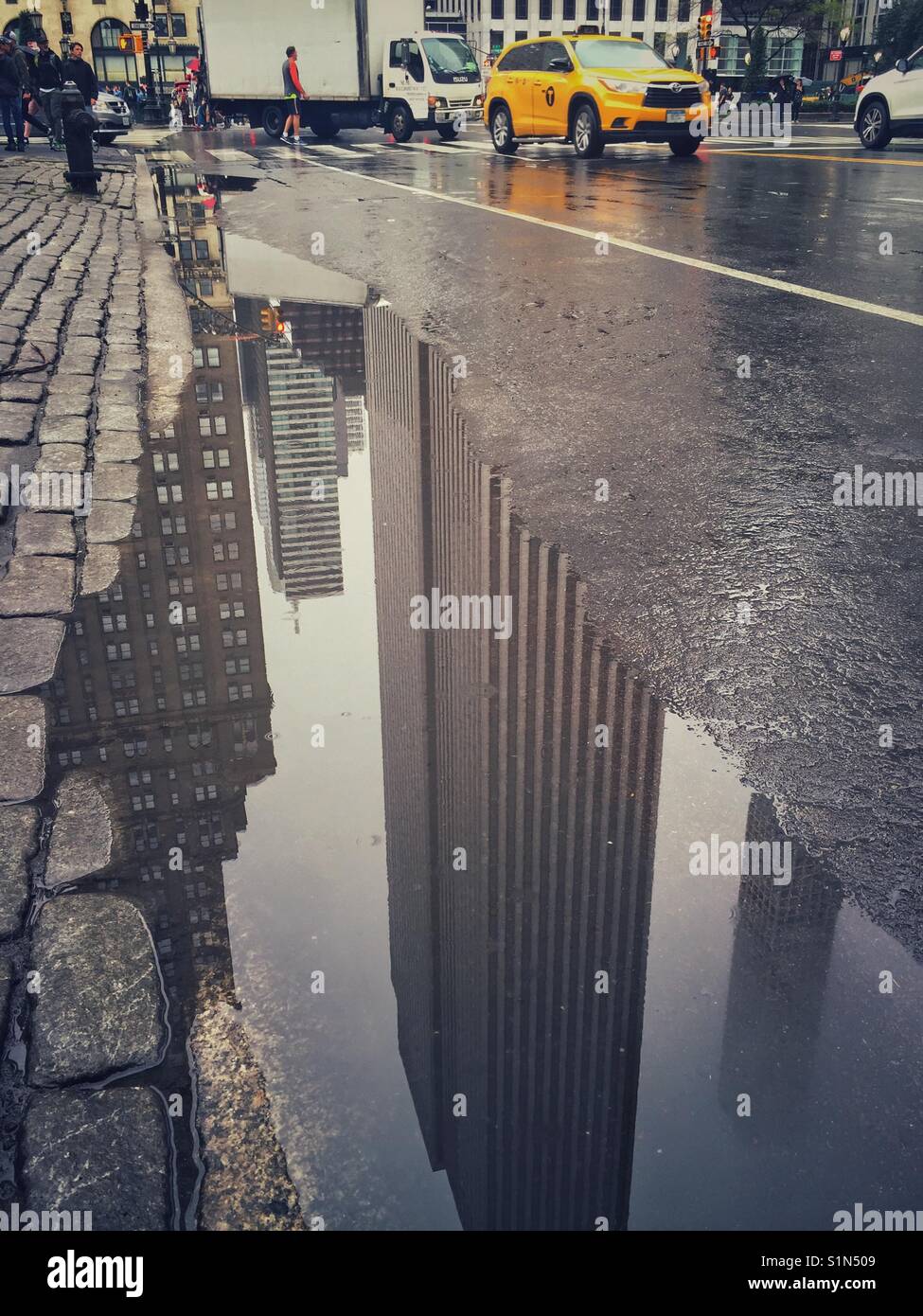 A large puddle of rainwater with the reflections of the New York City ...