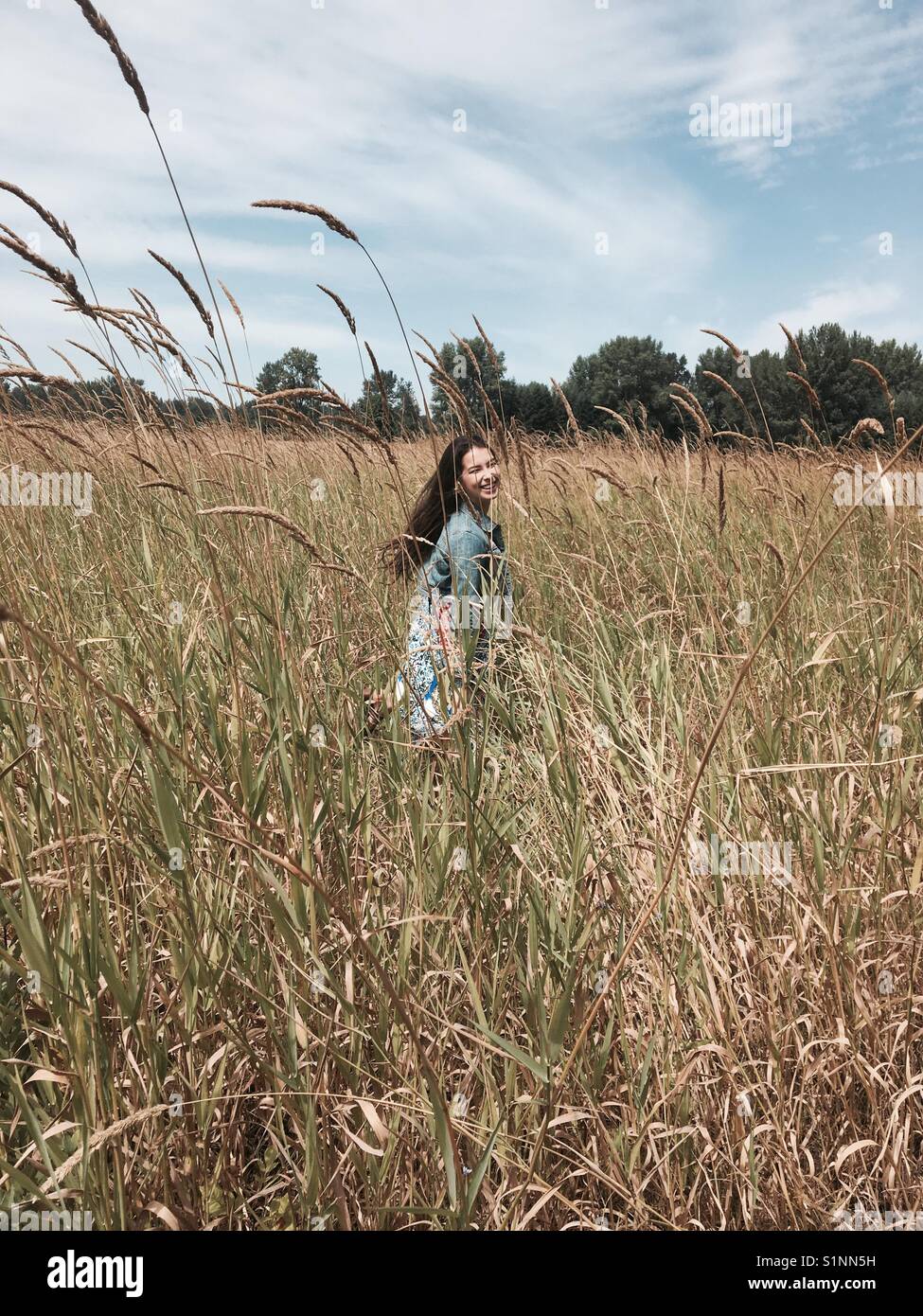 Girl looking back happily in the big field Stock Photo - Alamy