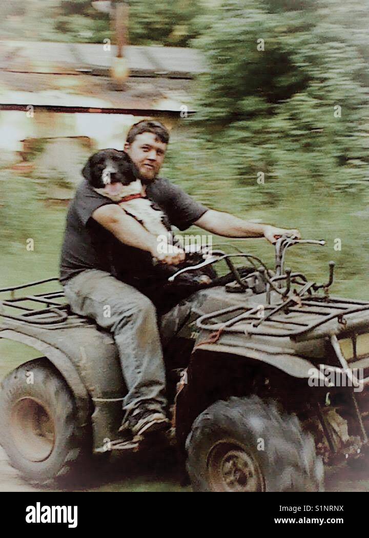 A man and his dog riding the four wheeler Stock Photo - Alamy