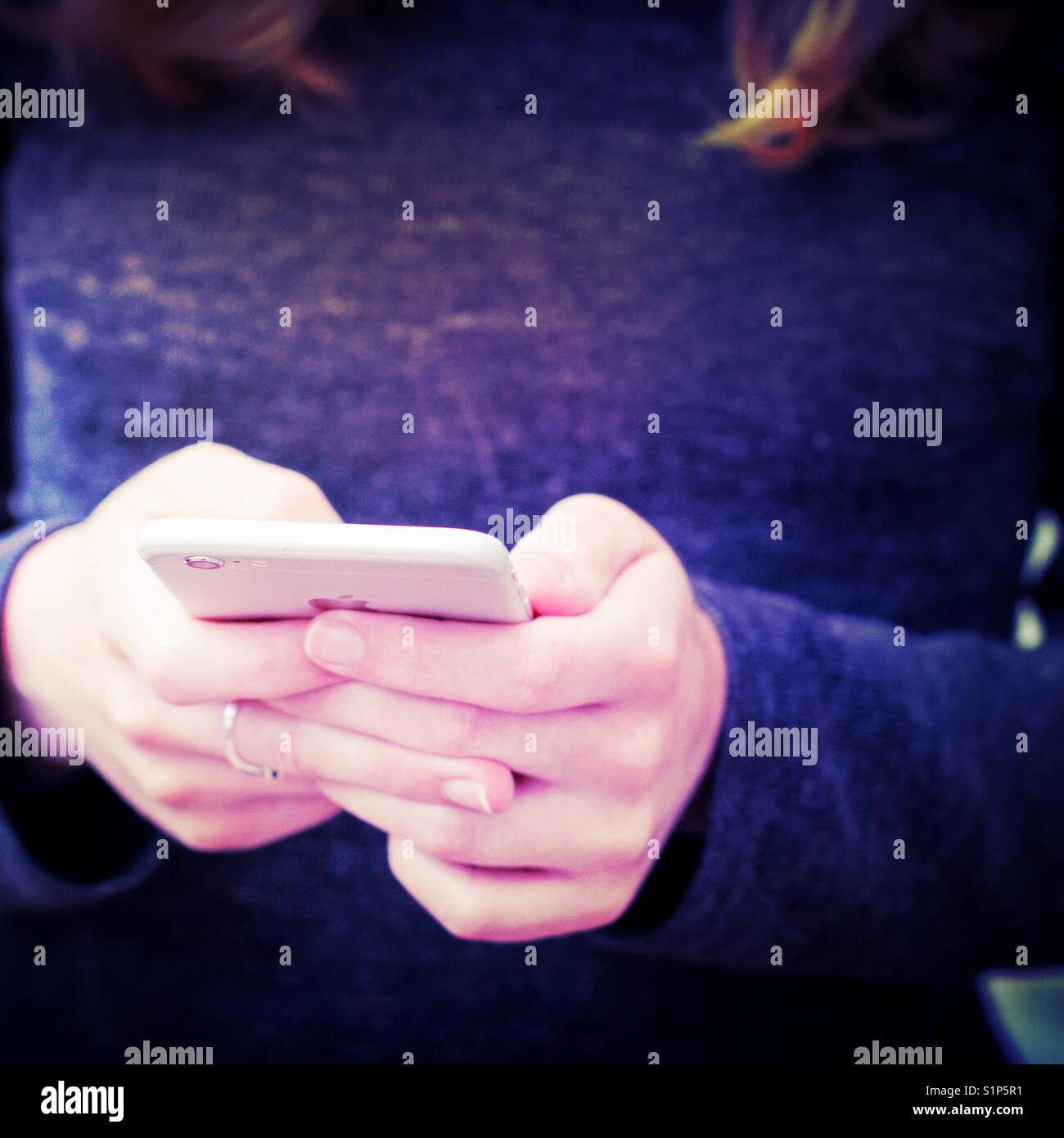 A mid section shot of a young girl holding her mobile phone in her ...