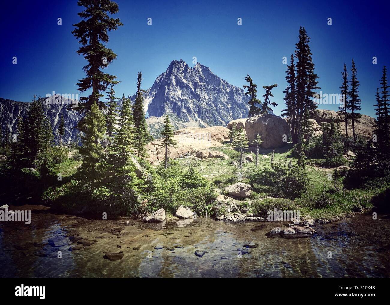 Edge of alpine lake with mountain background Stock Photo - Alamy