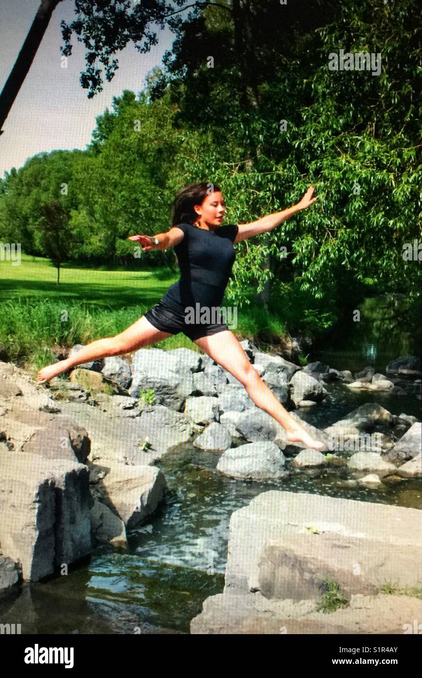 Woman jumping over a stream Stock Photo - Alamy