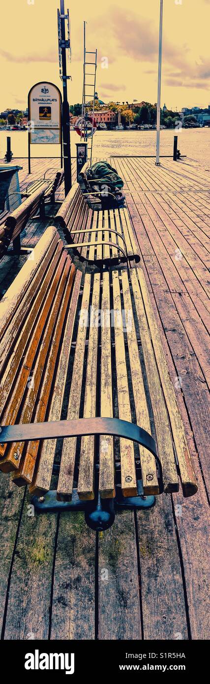Homeless person sleeping on bench on waterfront jetty, Stockholm ...
