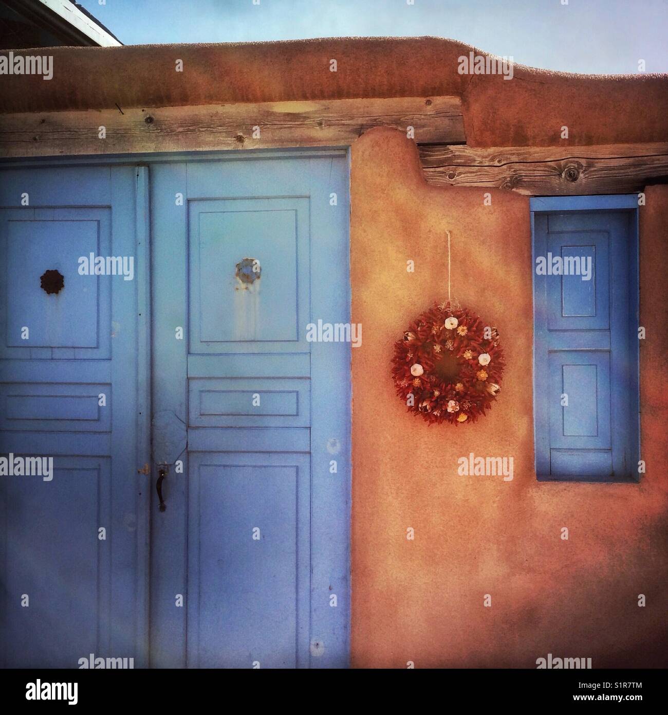 Afternoon sunlight streaks across the doors of an adobe house in the ...