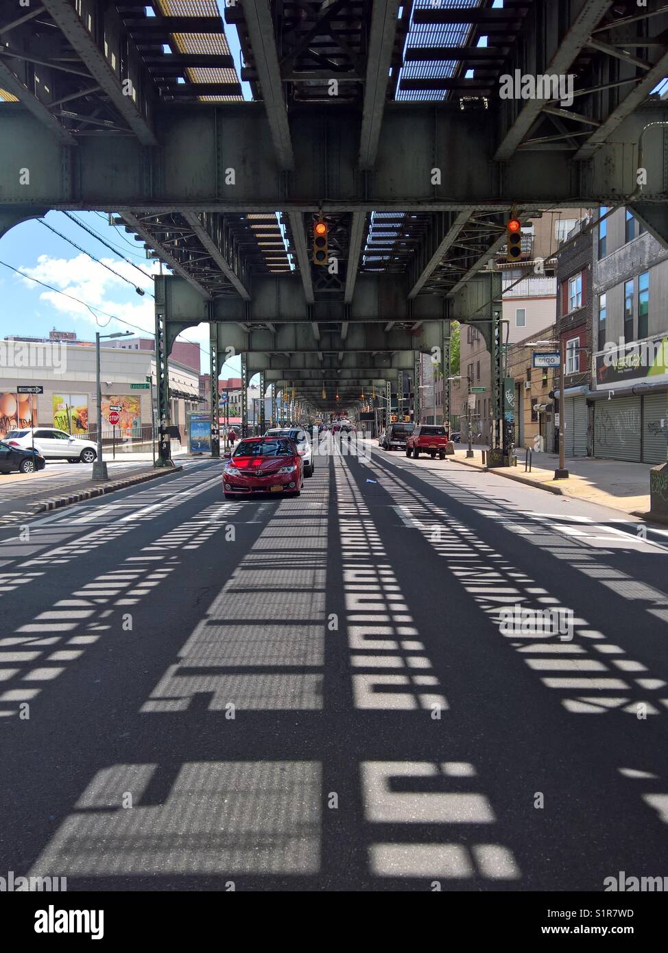 Cars passing under the elevated subway line over Broadway ave in ...