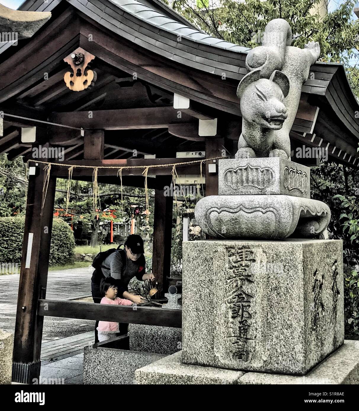 Mother and child at a chozubachi, water basin, performing purification ...