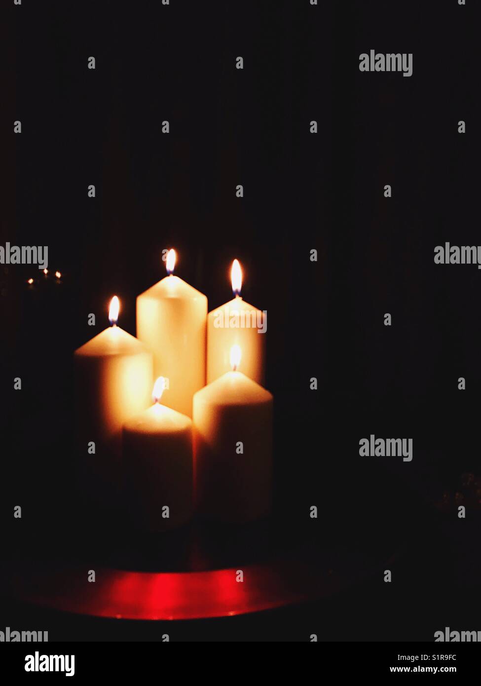 Five candles lit in the dark Stock Photo - Alamy
