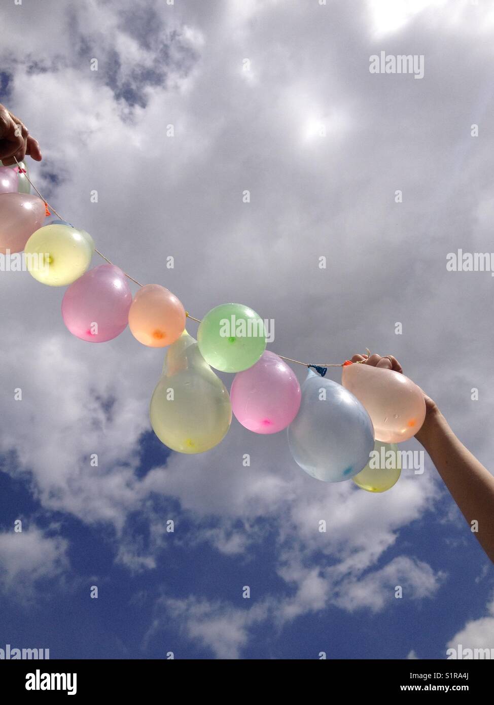 Holding up a string of balloons Stock Photo - Alamy