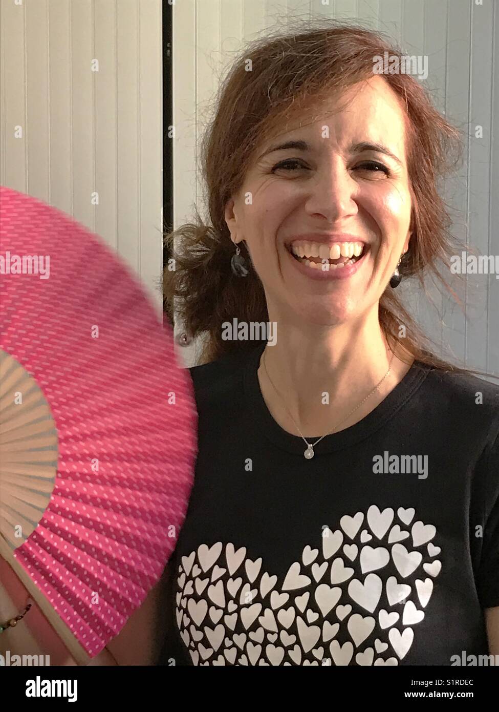 Woman smiling and fanning herself Stock Photo - Alamy