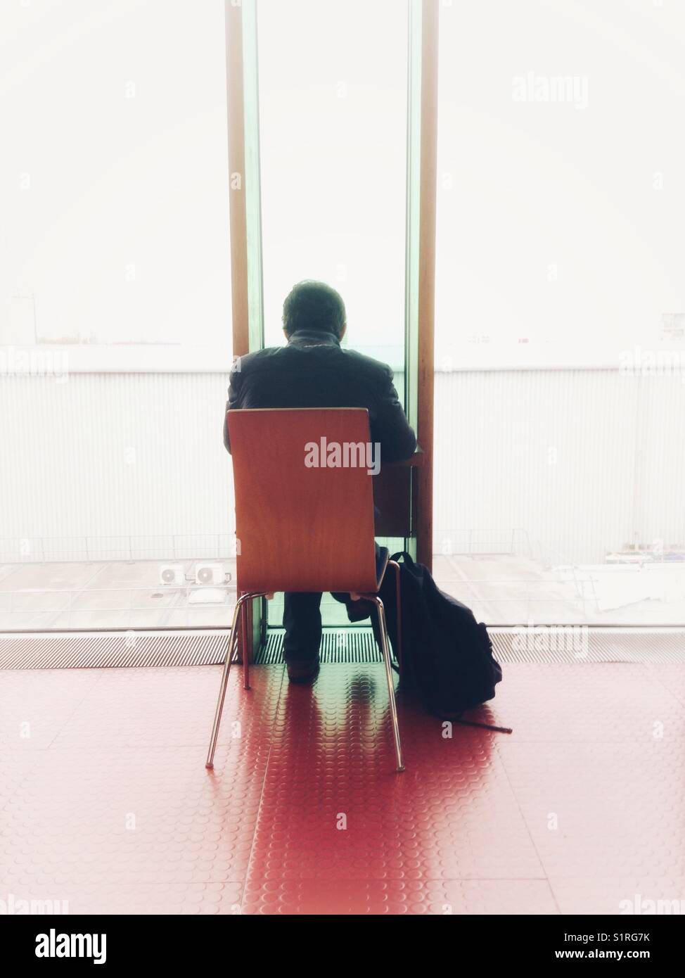 A man sitting alone looking out of the window Stock Photo - Alamy
