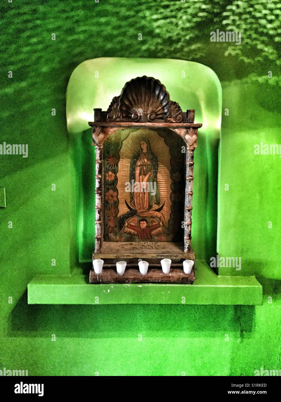 The Virgin Mary displayed in a green painted wall alter Stock Photo - Alamy