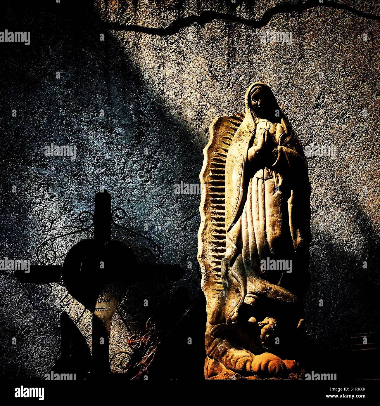 A cross and an image of Our Lady of Guadalupe decorate graves in a ...