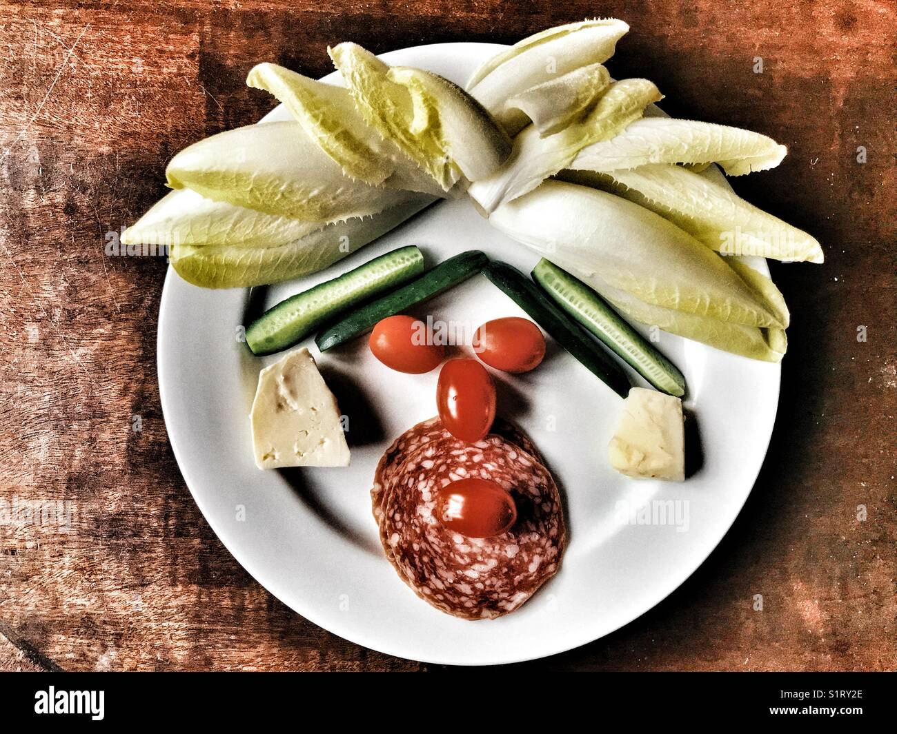Lunch of endives, cucumber, tomatoes, soft cheesecheese and salami on a ...