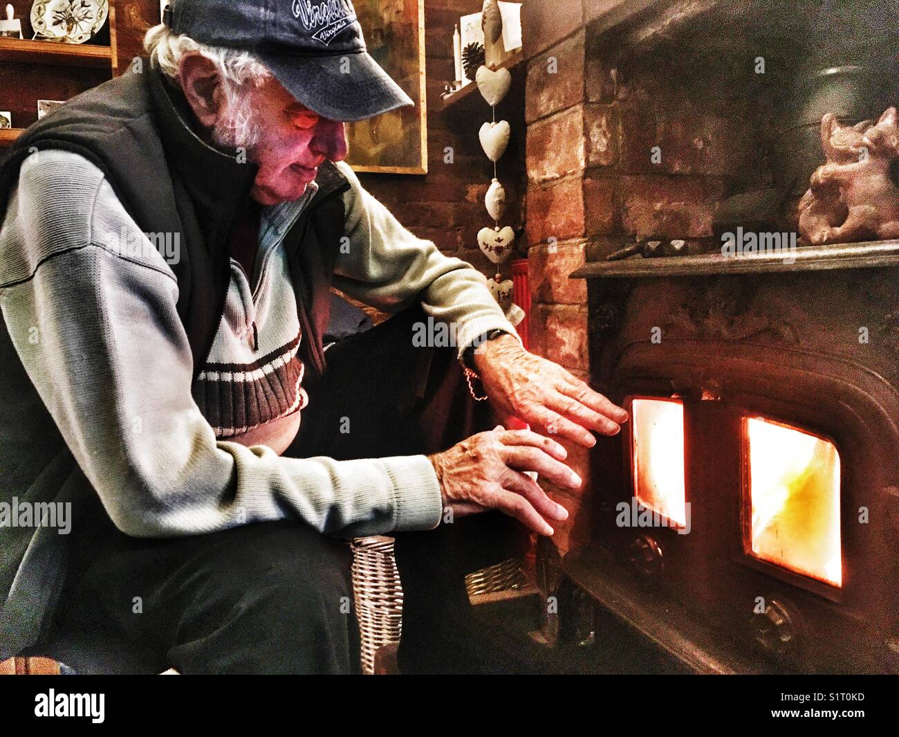 Elderly man keeping warm beside the fire Stock Photo - Alamy