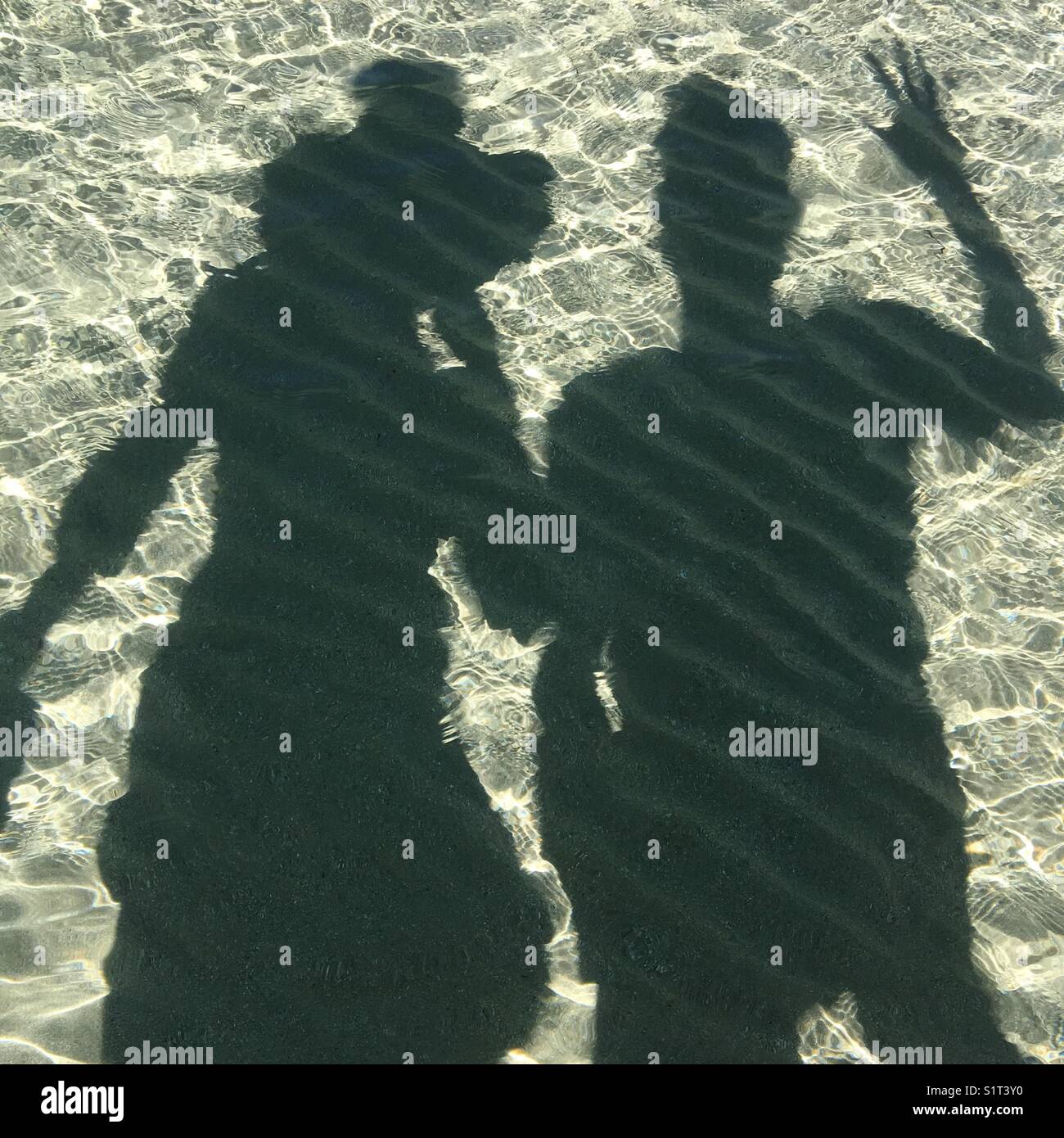 Shadows of a couple in shallow water at the beach Stock Photo - Alamy