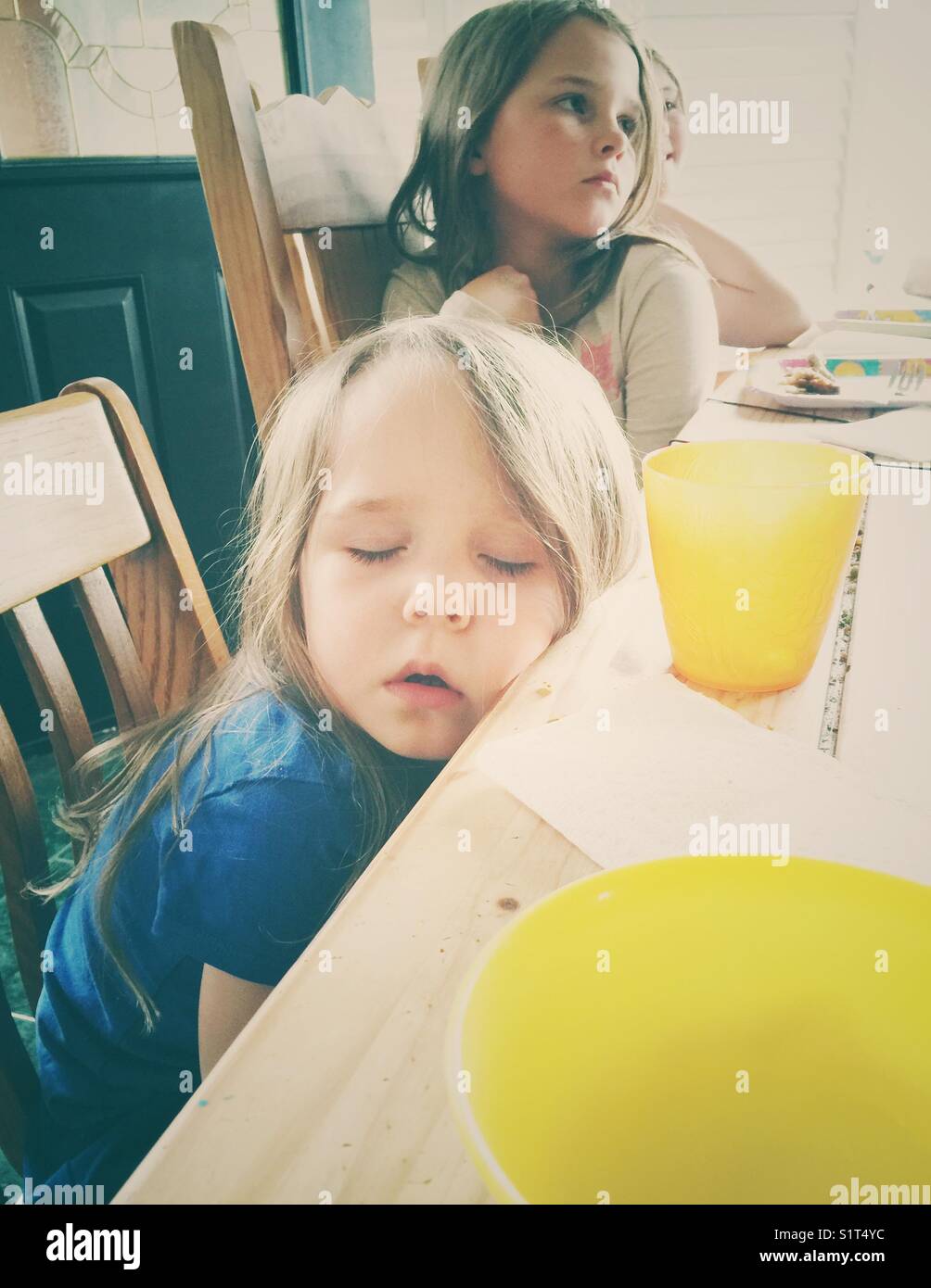 Toddler girl that has fallen asleep at the dining table with her ...