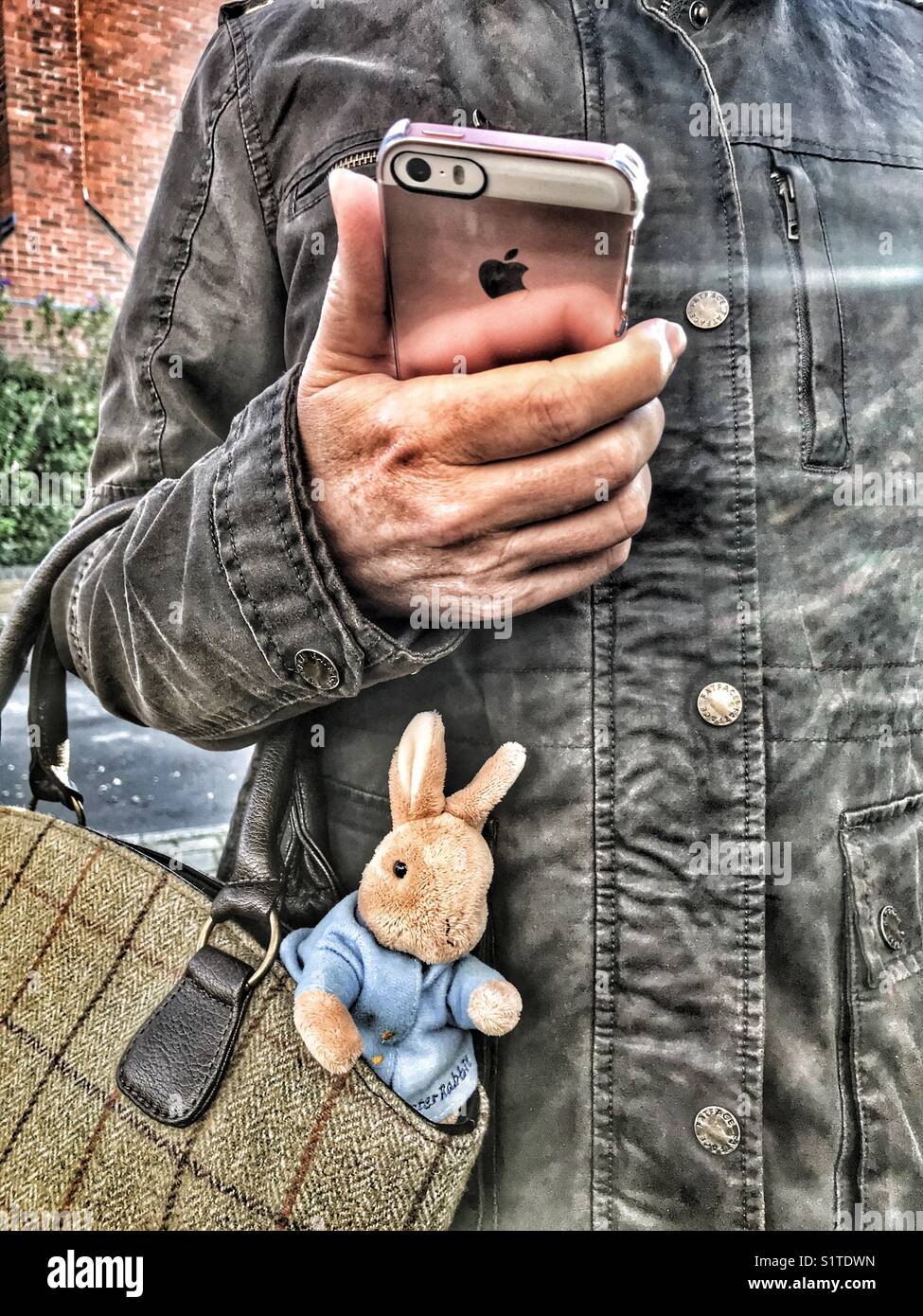 Working mother, using mobile phone and with a toy rabbit sticking out ...