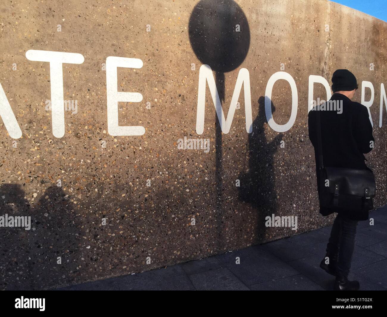 A man walks past a Tate Modern sign on a wall outside Tate Modern in ...