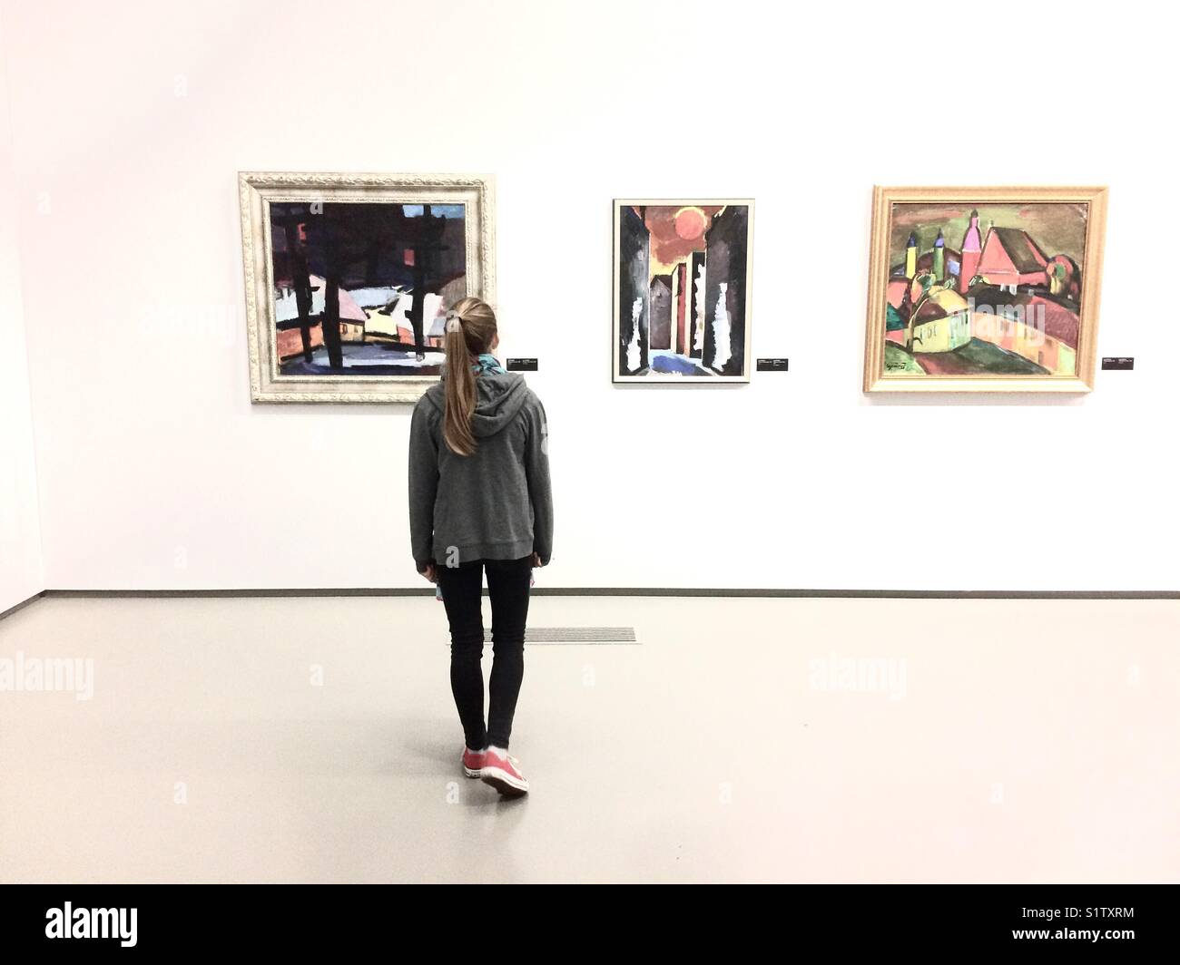 Teenage girl looking at paintings at art exhibition Stock Photo - Alamy