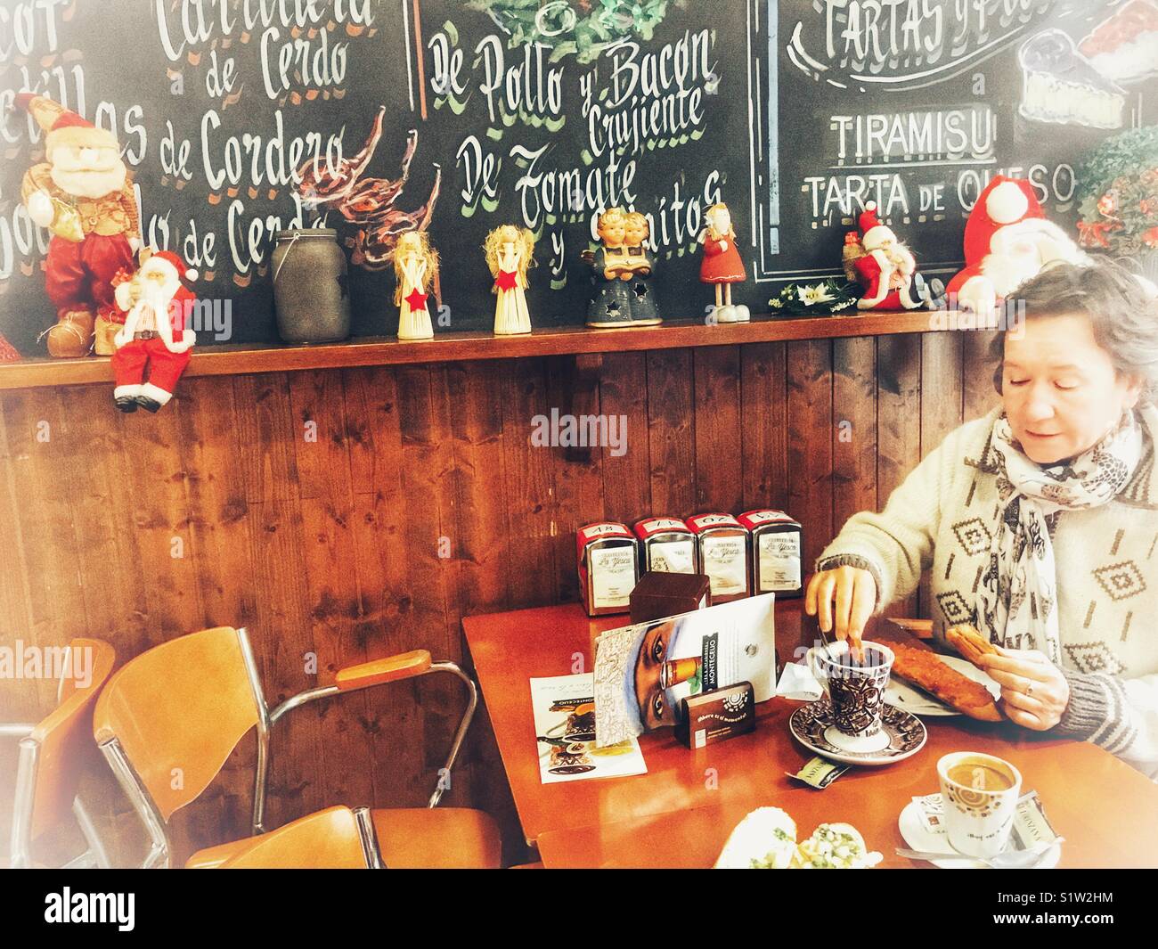 Woman seated at a table with her breakfast in a Spanish cafe, with the ...
