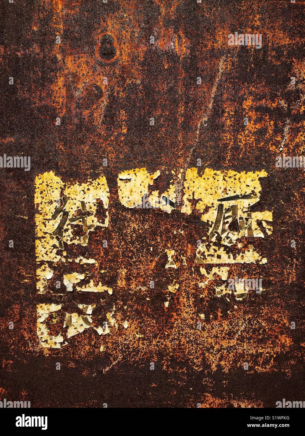 Remnants of paper sign distressed by weather on a rusty iron sheet wall ...