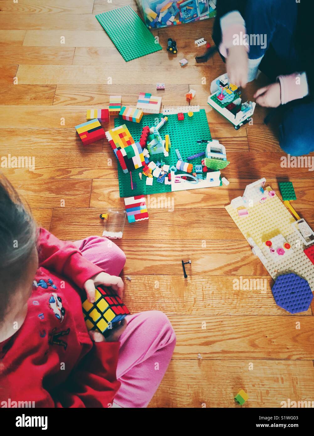 From above view of two young children playing with Rubik’s cube and ...