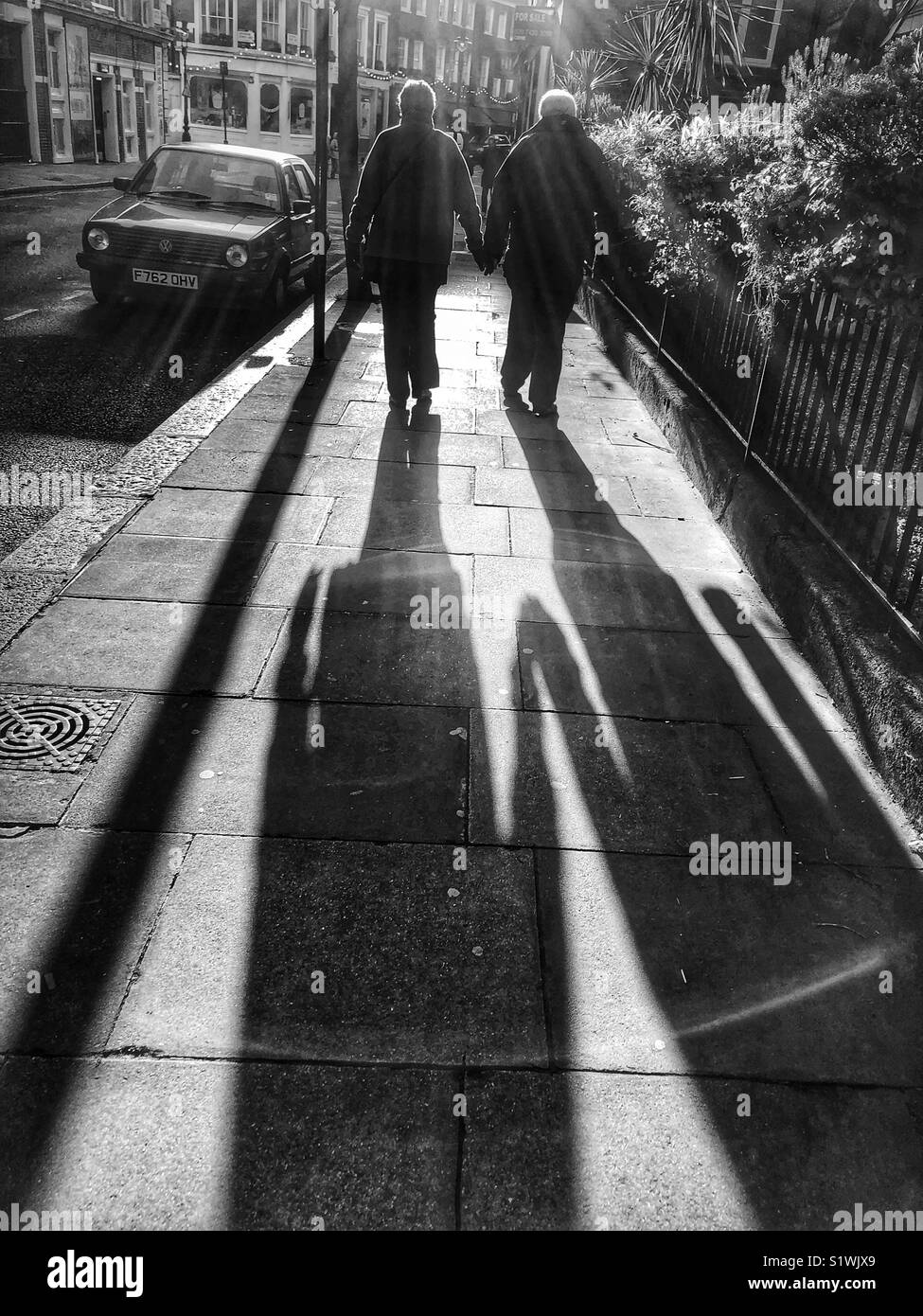 Couple walking holding hands in shadow Stock Photo - Alamy