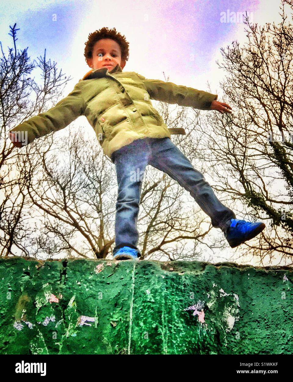 A little boy balancing atop a wall Stock Photo - Alamy