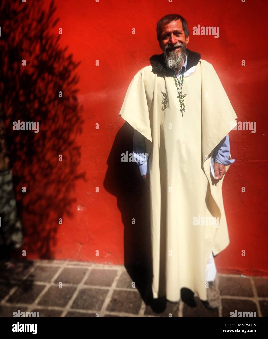 A man dressed as a monk in front of a red wall in Guanajuato, Mexico ...