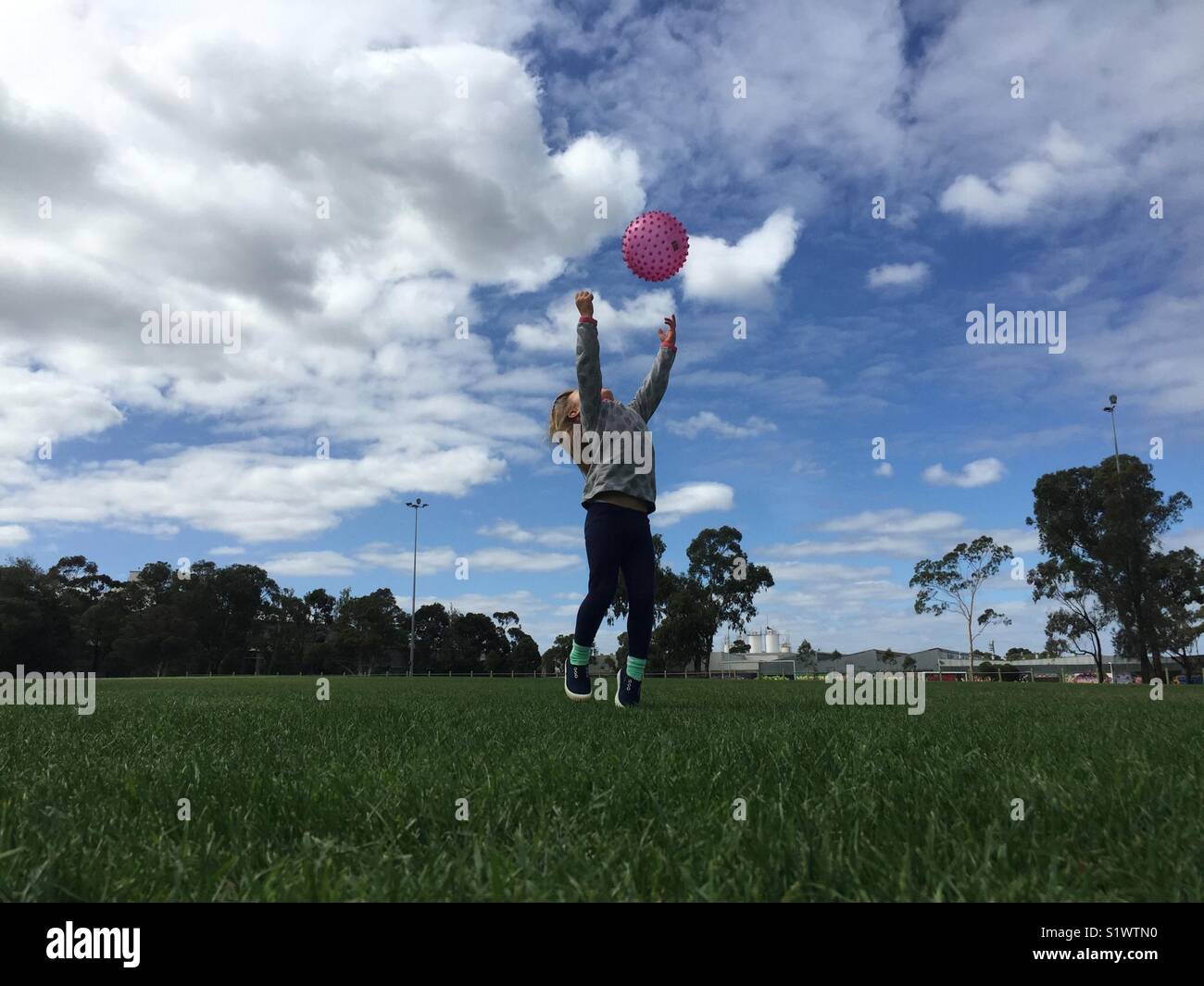 Kid jumping for pink ball Stock Photo - Alamy