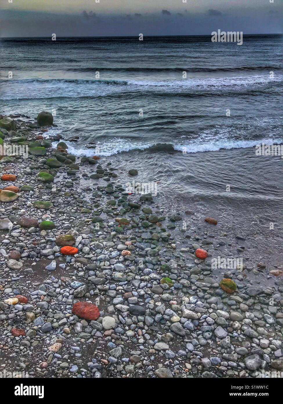 Volcanic black sand at the river mouth with a storm brewing out to sea ...