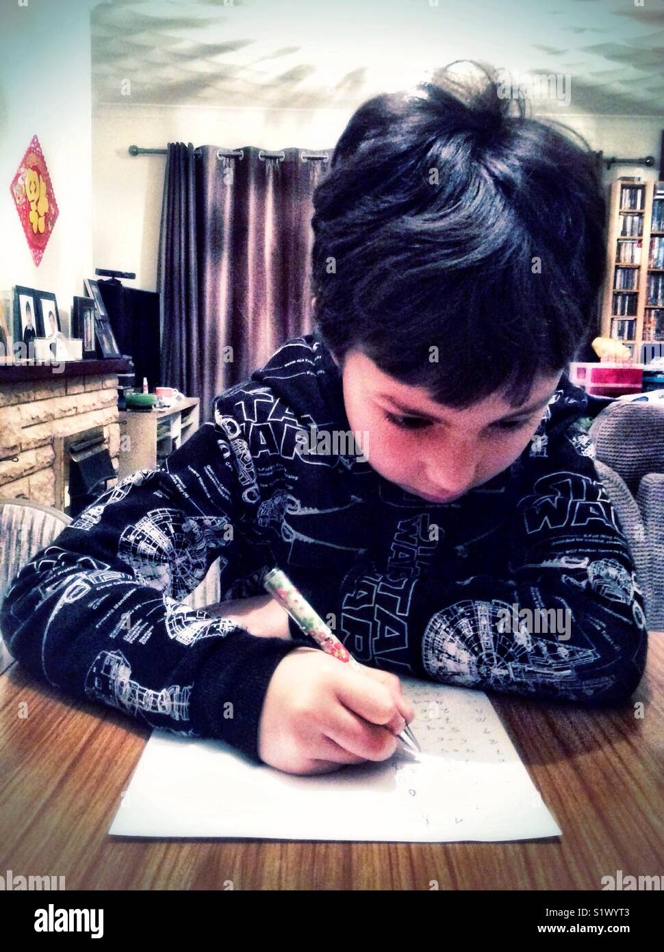 A young boy sat at a dining room table doing his homework Stock Photo ...