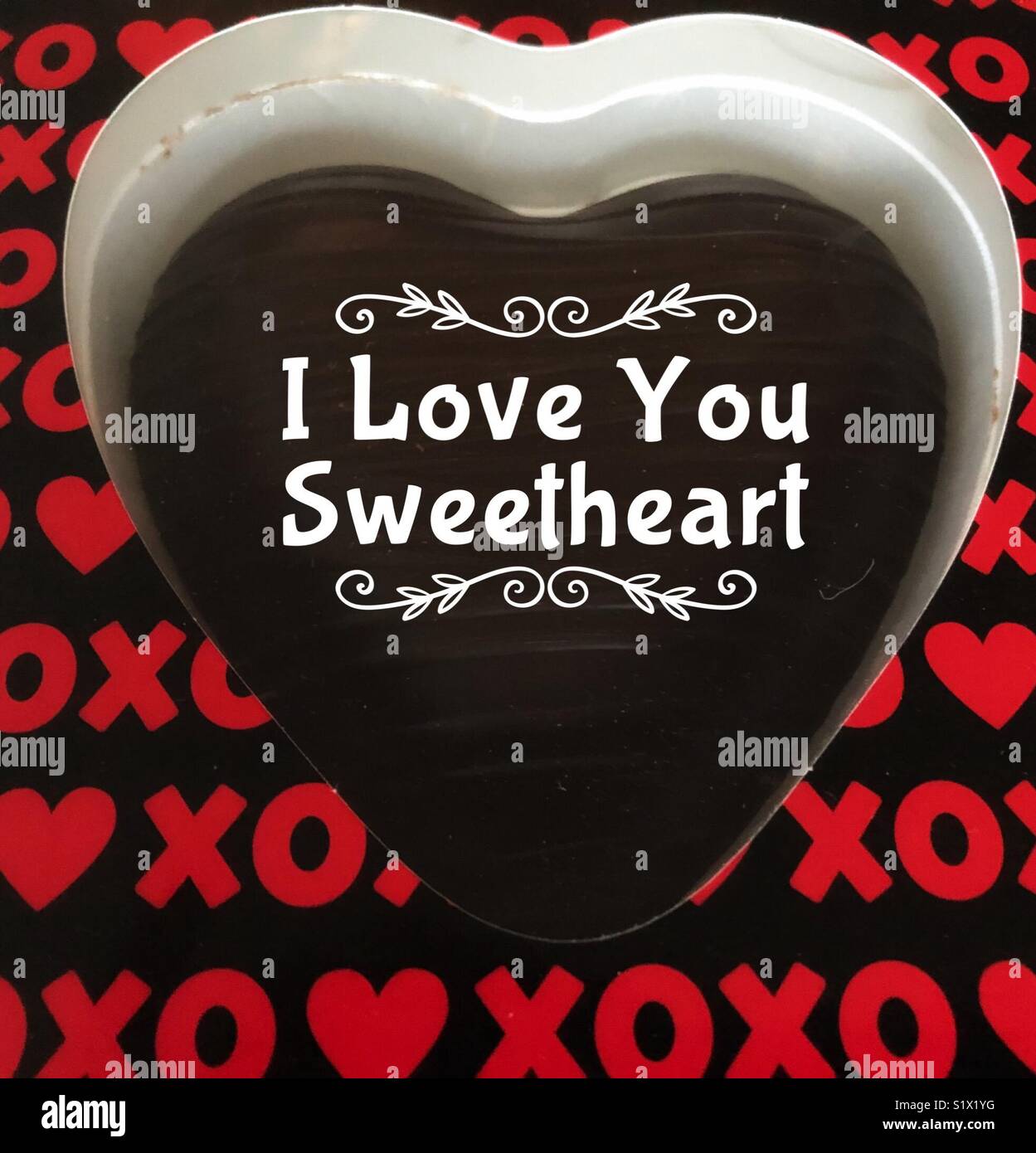 Dark chocolate heart with the words “I love you sweetheart” written on ...