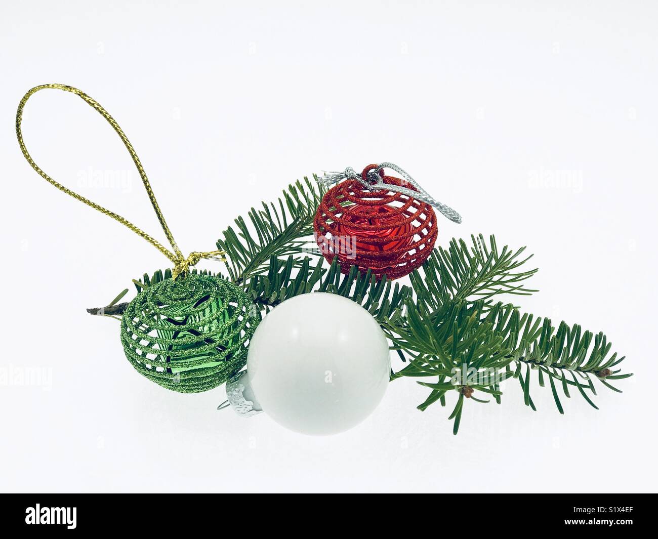 Three Christmas ornaments and a sprig of a fir tree isolated on a white ...